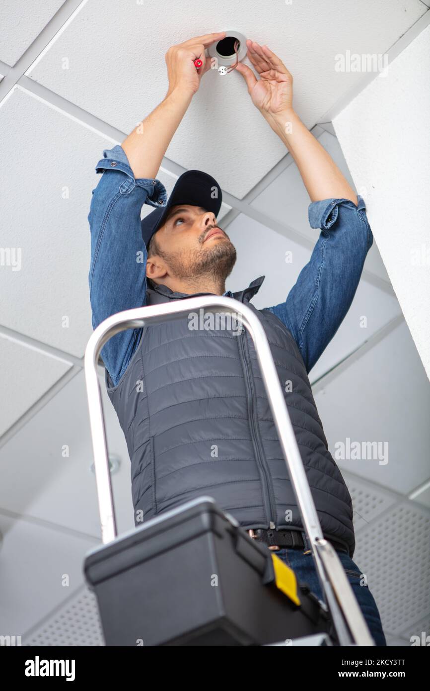 man standing on ladder changing a lightbulb Stock Photo - Alamy