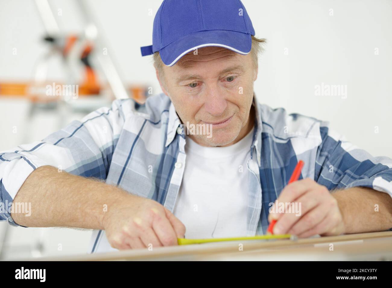 senior man as a carpenter measuring wood Stock Photo - Alamy