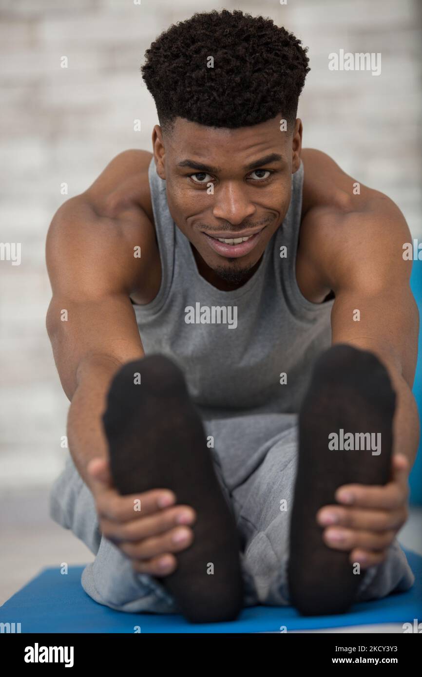 focused mid adult man stretching leg while practicing yoga Stock Photo ...