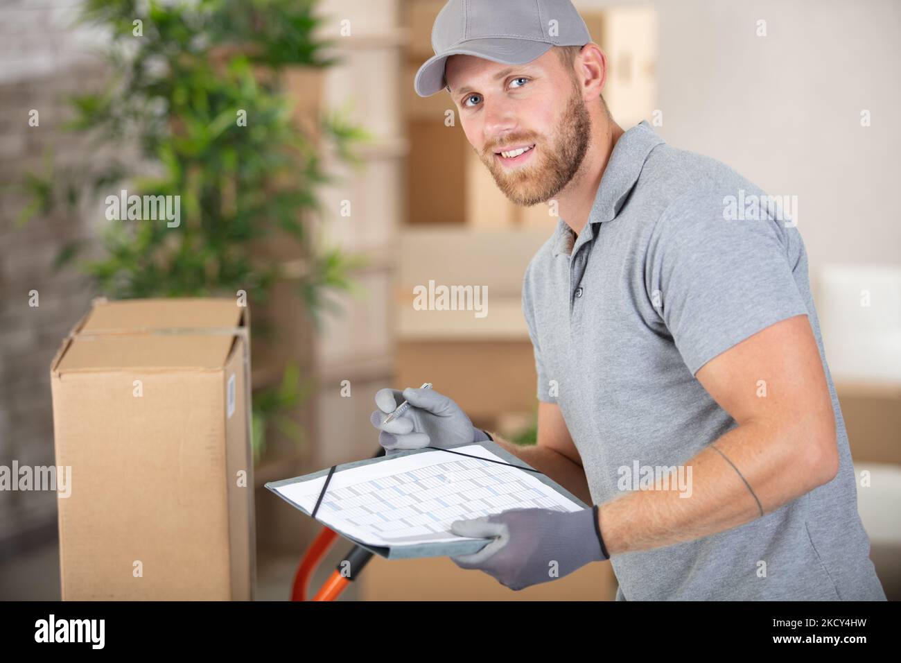 delivery man with clipboard and parcels on trolley Stock Photo - Alamy