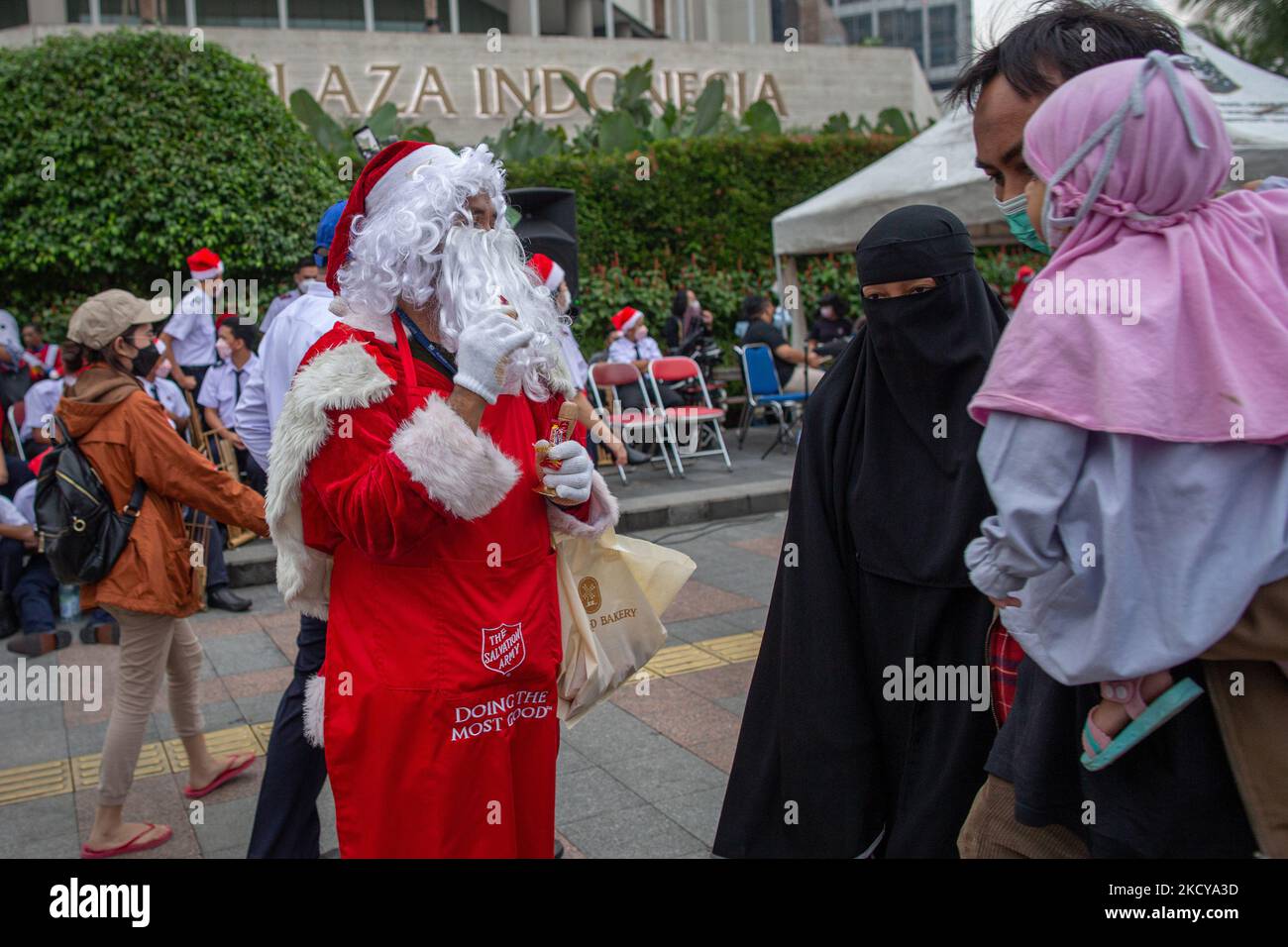 A man dressed as Santa Claus talks to a Muslim woman during ...