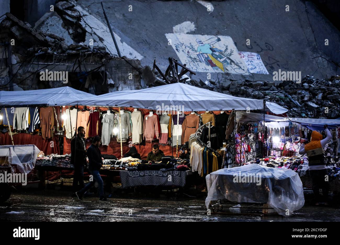 A Palestinian sells clothes at the tent in the street next a destroyed ...