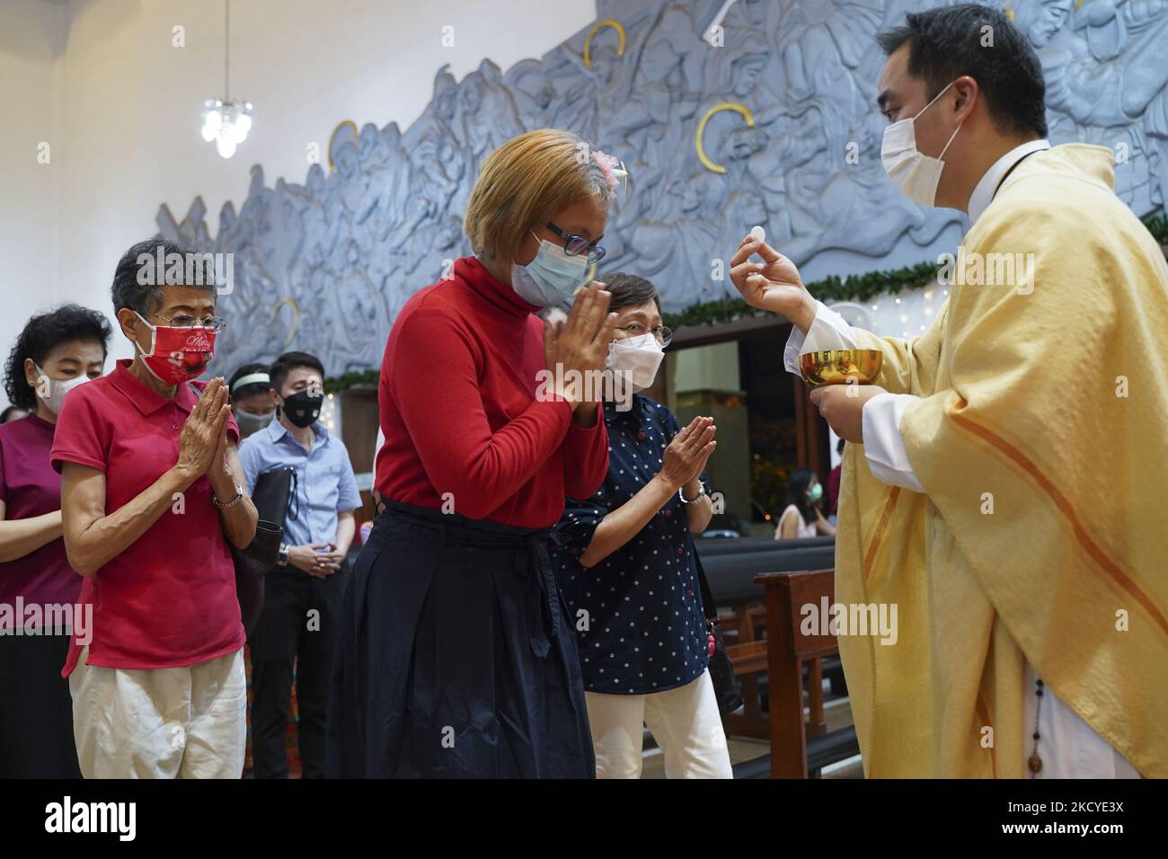 Thai Catholic priests offer the communion wafer to church goers during ...