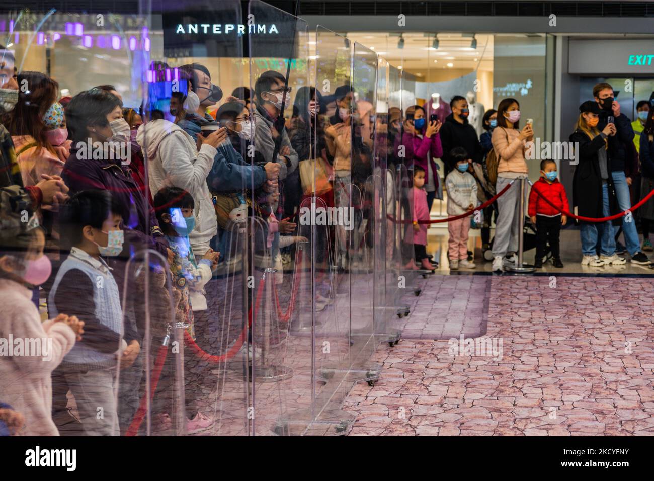 Customers watch a show at the Festival Walk mall behind plexiglas ...