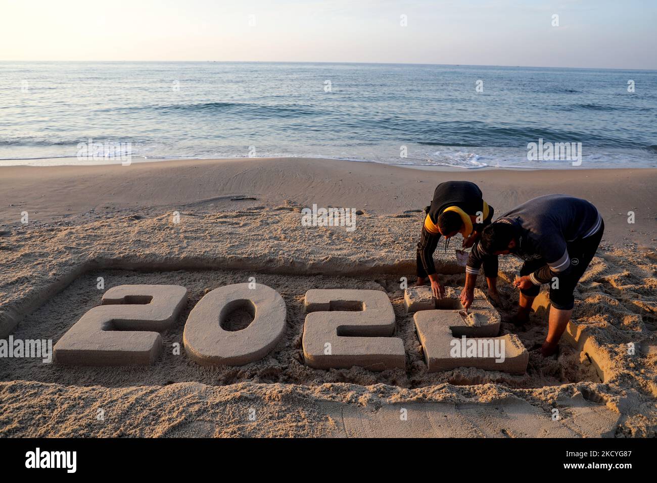 Palestinian artists work on a sand sculpture writes in the sand ...