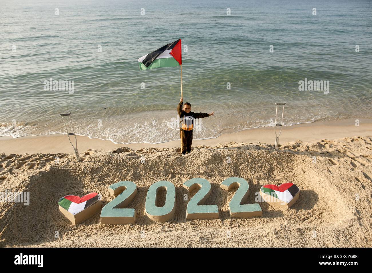 A Palestinian boy hold a palestinian flag on the beach behind a Sand ...