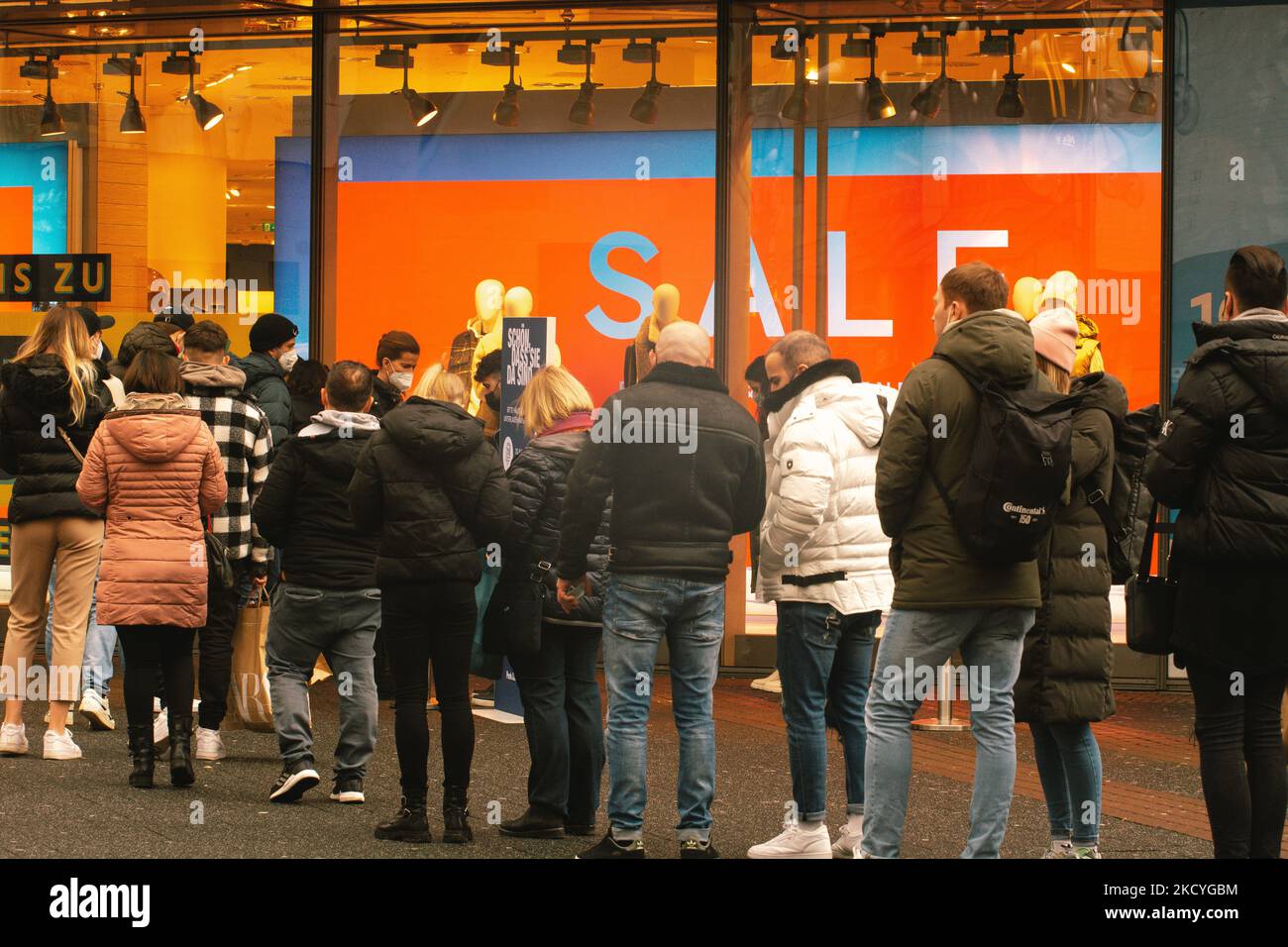 people wait in a long line to enter a retailer store in the city center ...