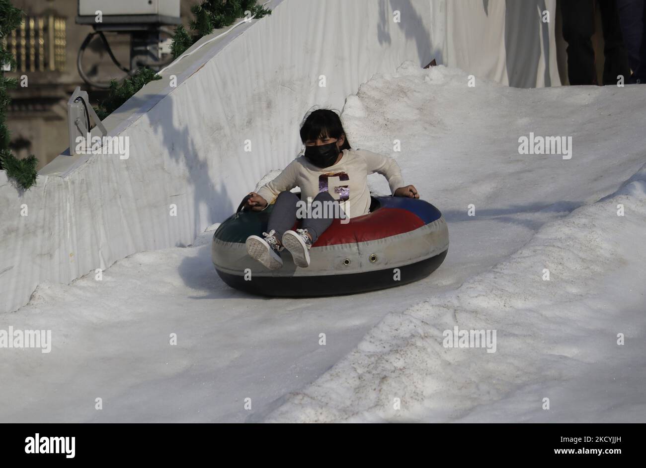 A child on a tyre descending from an artificial ice ramp in Mexico City ...