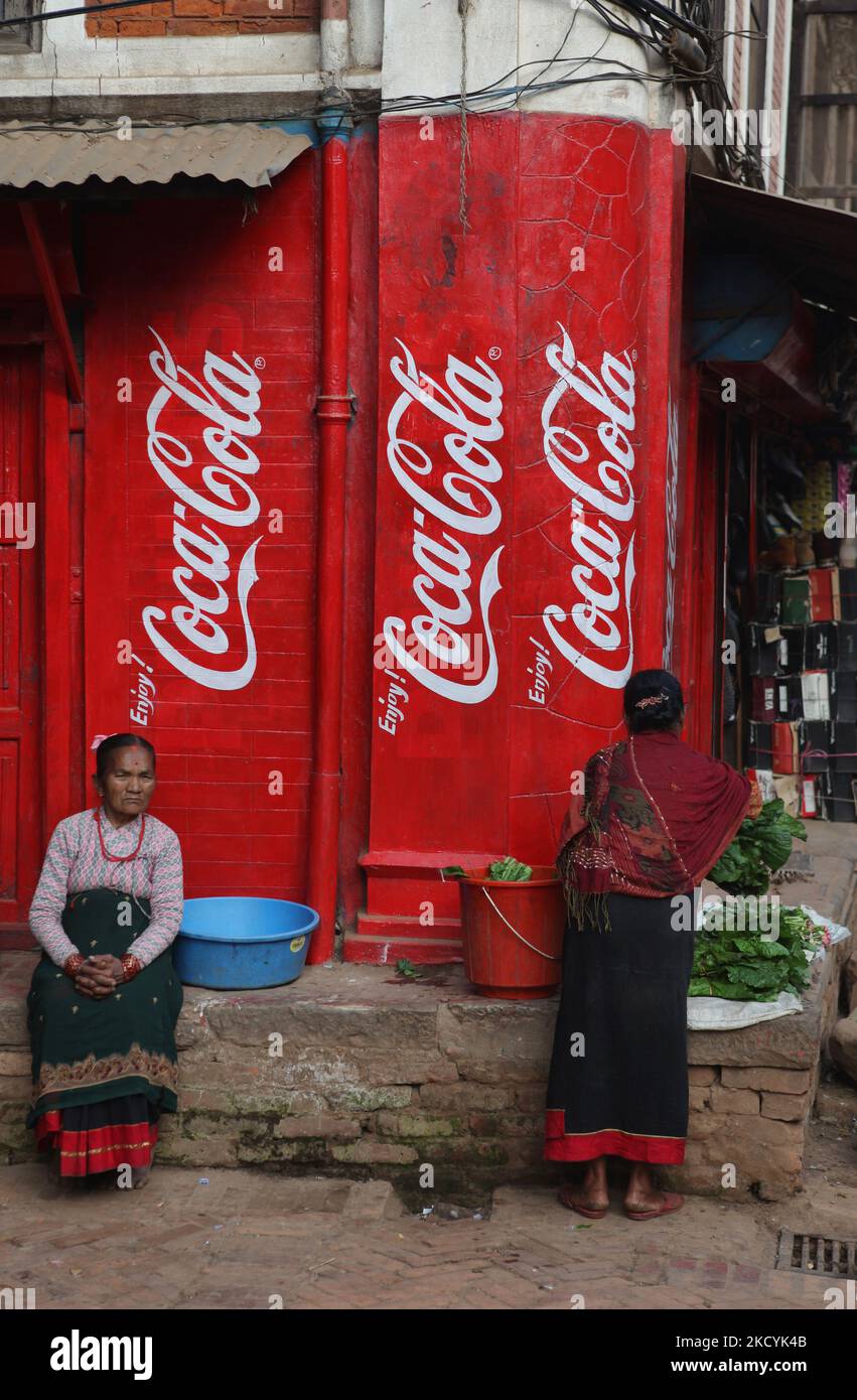 Newari women in traditional attire sit in front of a shop with Coke ...