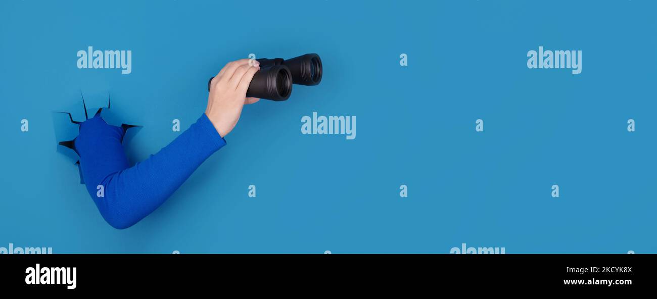 hand holding binoculars over blue background, panoramic layout Stock ...