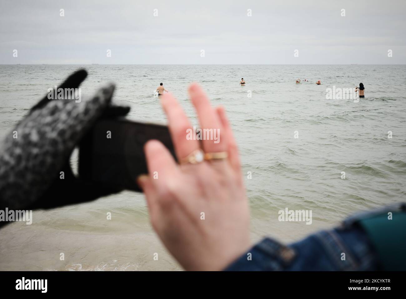 A woman takes a photograph of cold water swimmers in Gdansk, Poland on ...