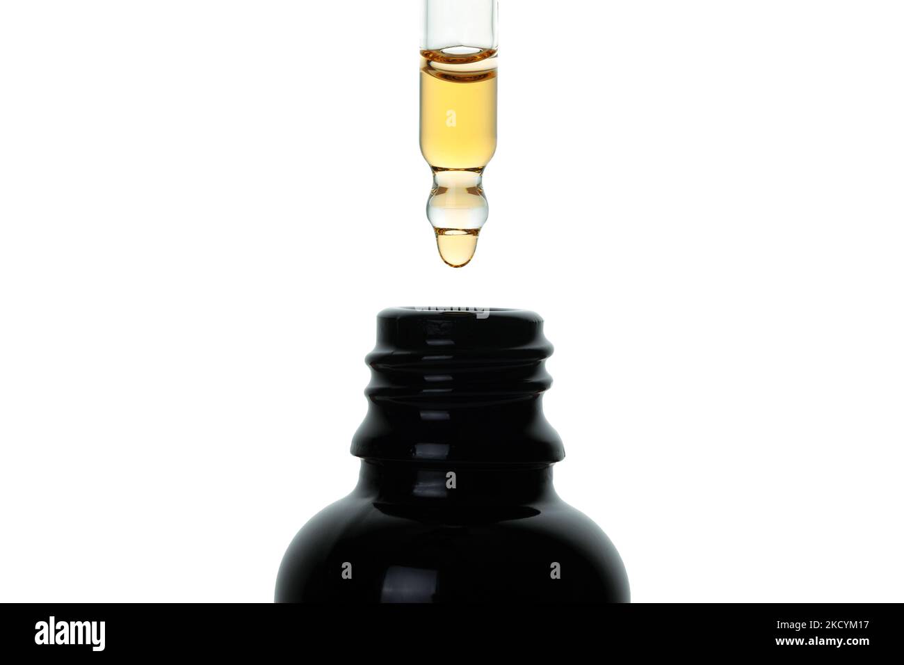 Yellow essential serum oil dripping from gold dropper isolated on white ...