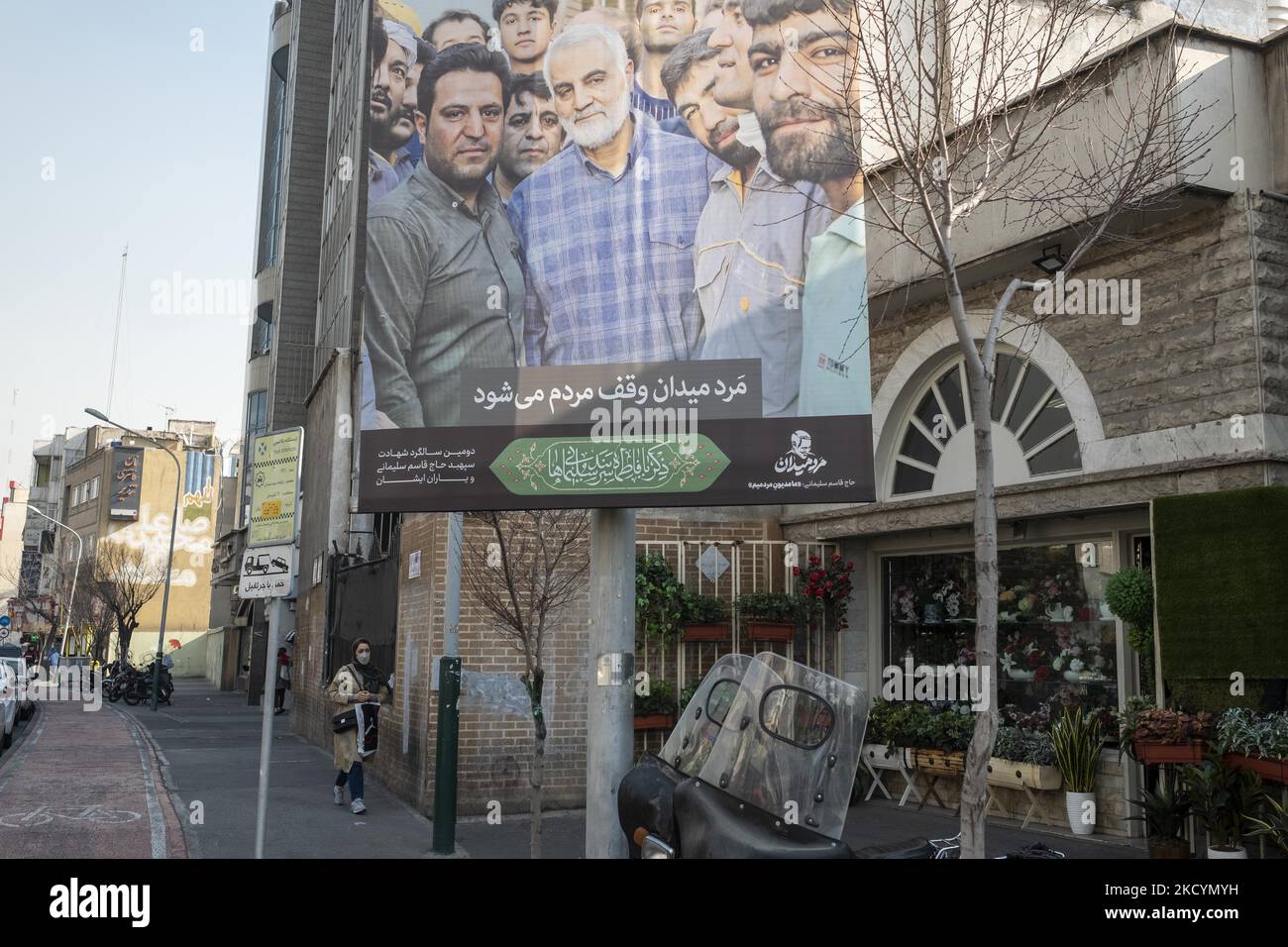 An Iranian woman wearing a protective face mask walks under a billboard ...