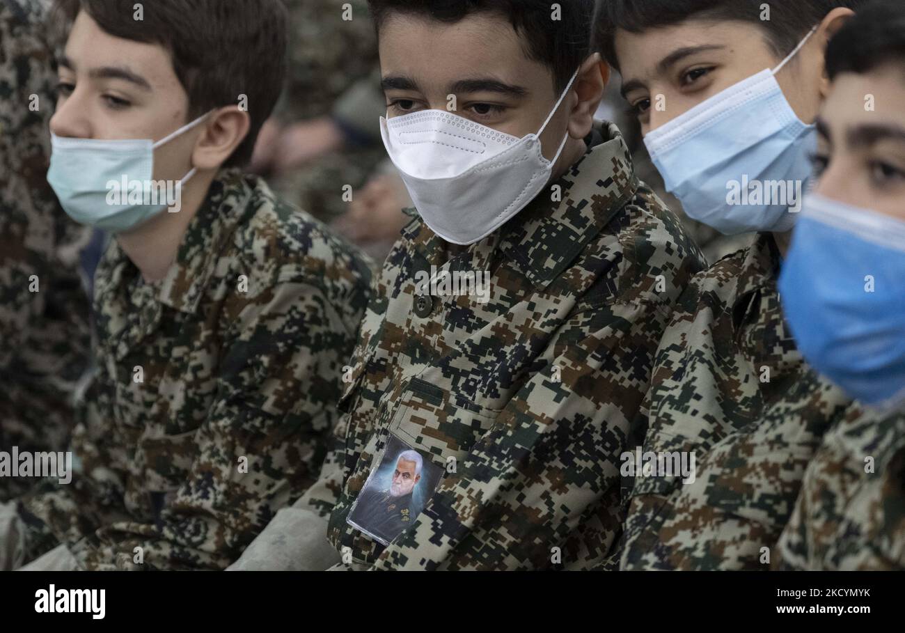 Iranian young boys in military uniforms wearing protective face masks ...