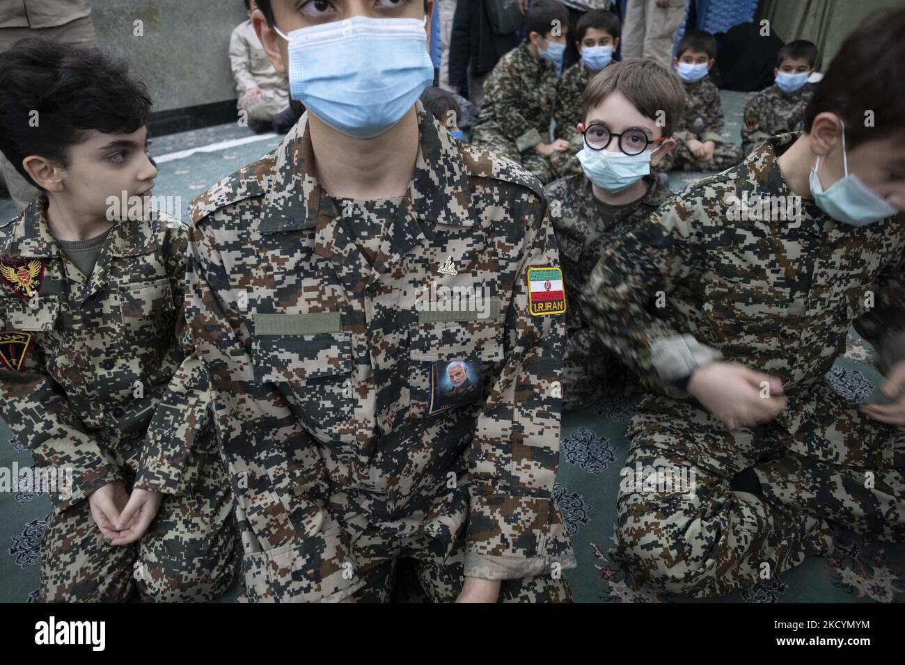 An Iranian young boy in military uniforms wearing an Iran flag and a ...
