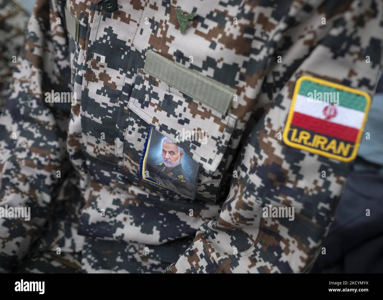 An Iranian young boy in military uniforms wearing an Iran flag and a ...