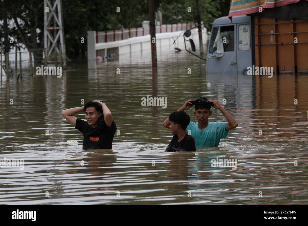 People are seen walking through floods caused by an overflowing river ...