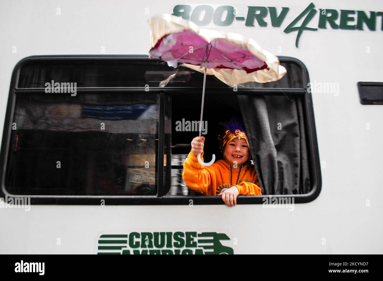 A little girl sticks her umbrella out a side window of an RV as she ...