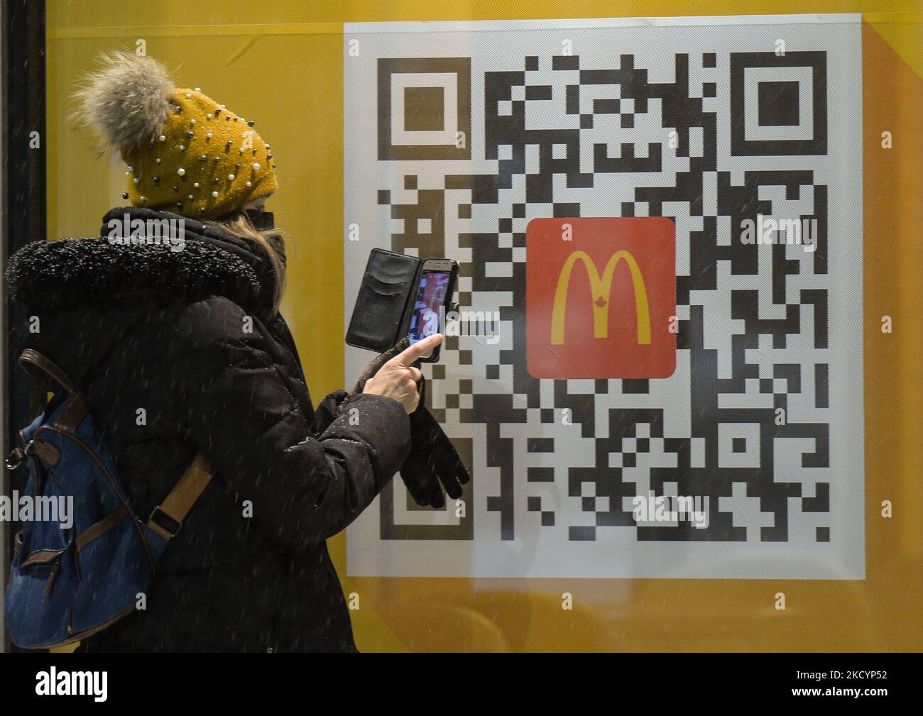 A woman checks the QR code with her mobile phone outside a McDonald's ...