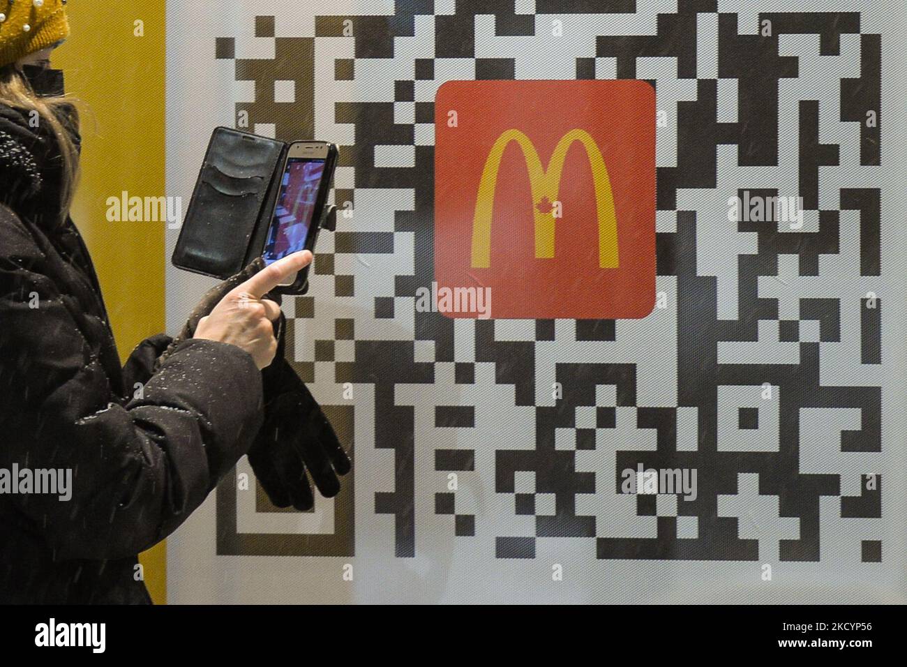 A woman checks the QR code with her mobile phone outside a McDonald's ...