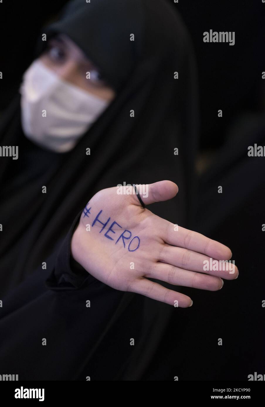 An Iranian veiled woman holds up her hand with a hashtag which is a ...