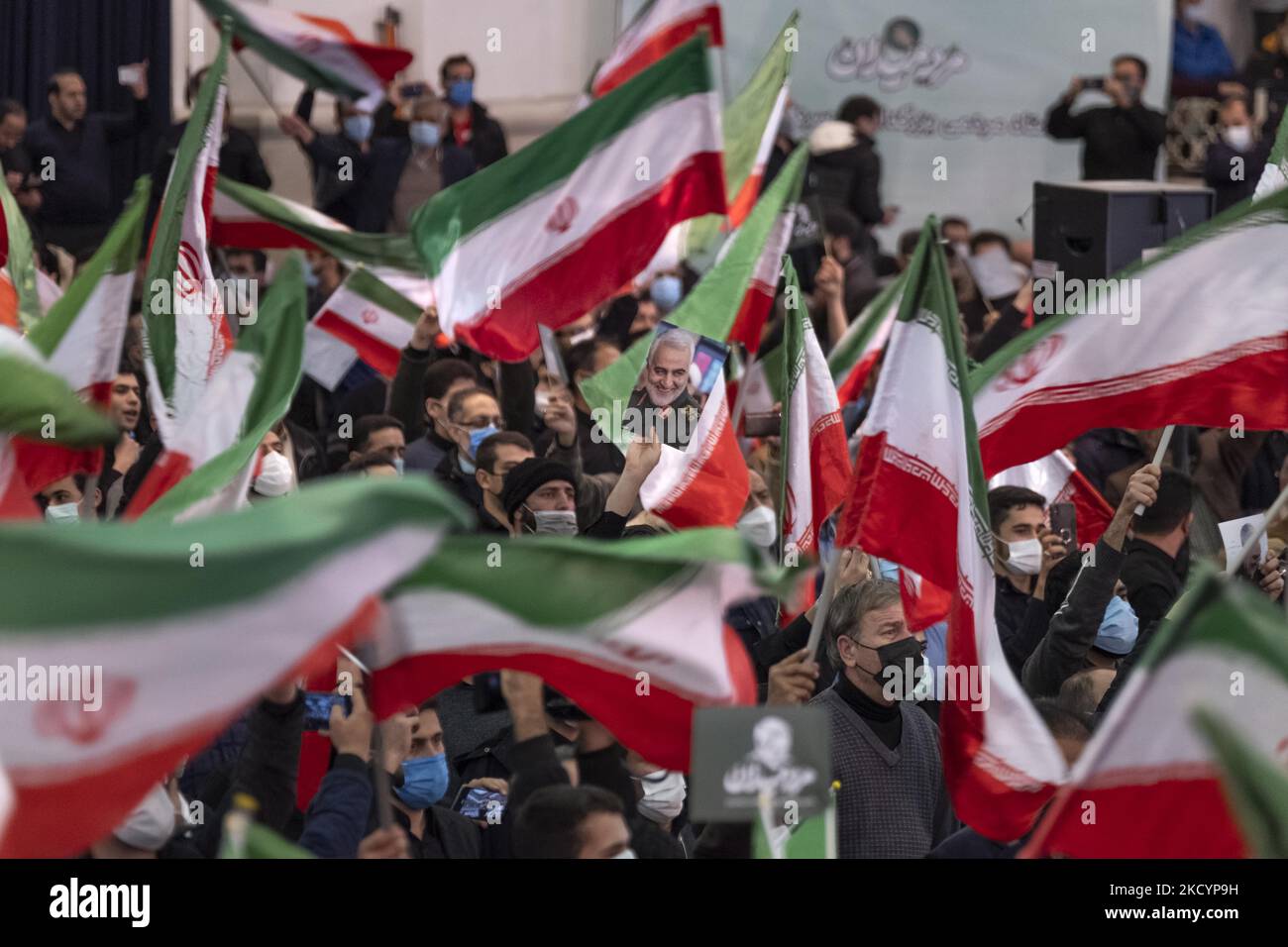 Iranian men wave Iran flags as one of them holds-up a portrait of ...