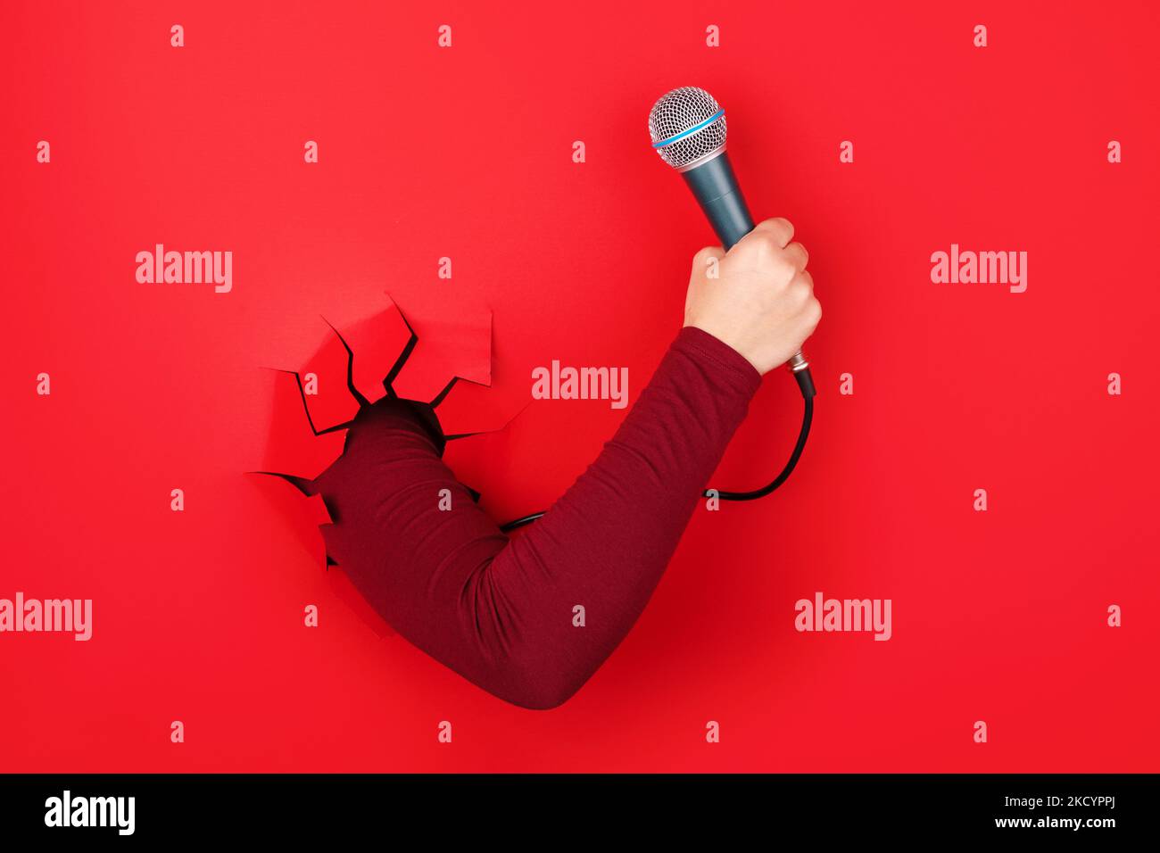 microphone in hand over red background Stock Photo - Alamy
