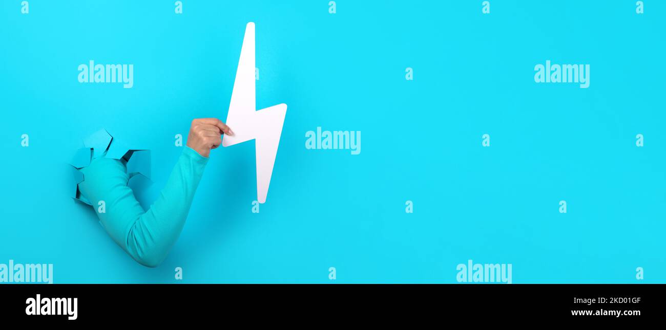 hand holding lightning bolt over blue background, panoramic layout ...