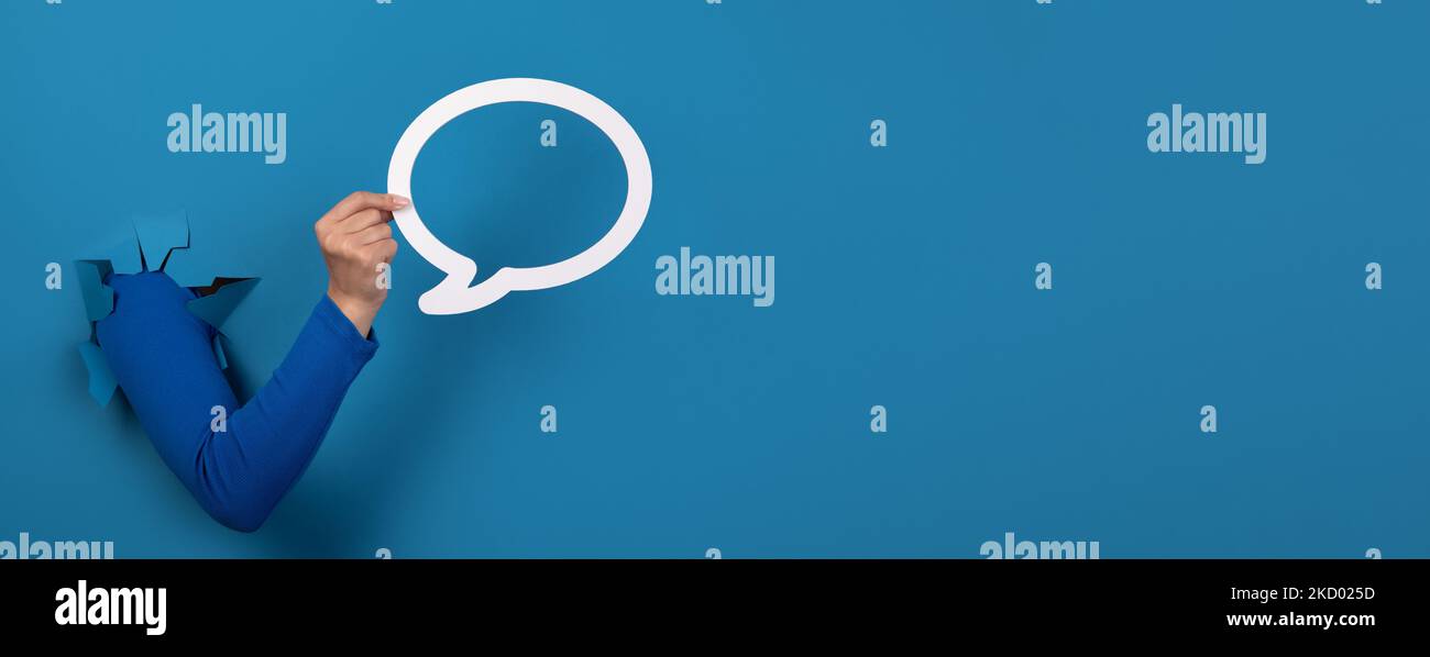 Talk bubble speech icon in hand over blue background, panoramic layout ...