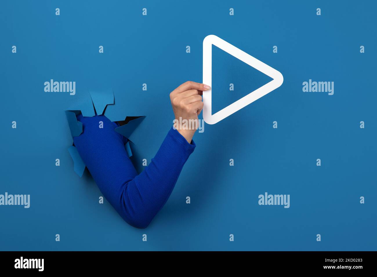hand holding play button over blue background Stock Photo - Alamy