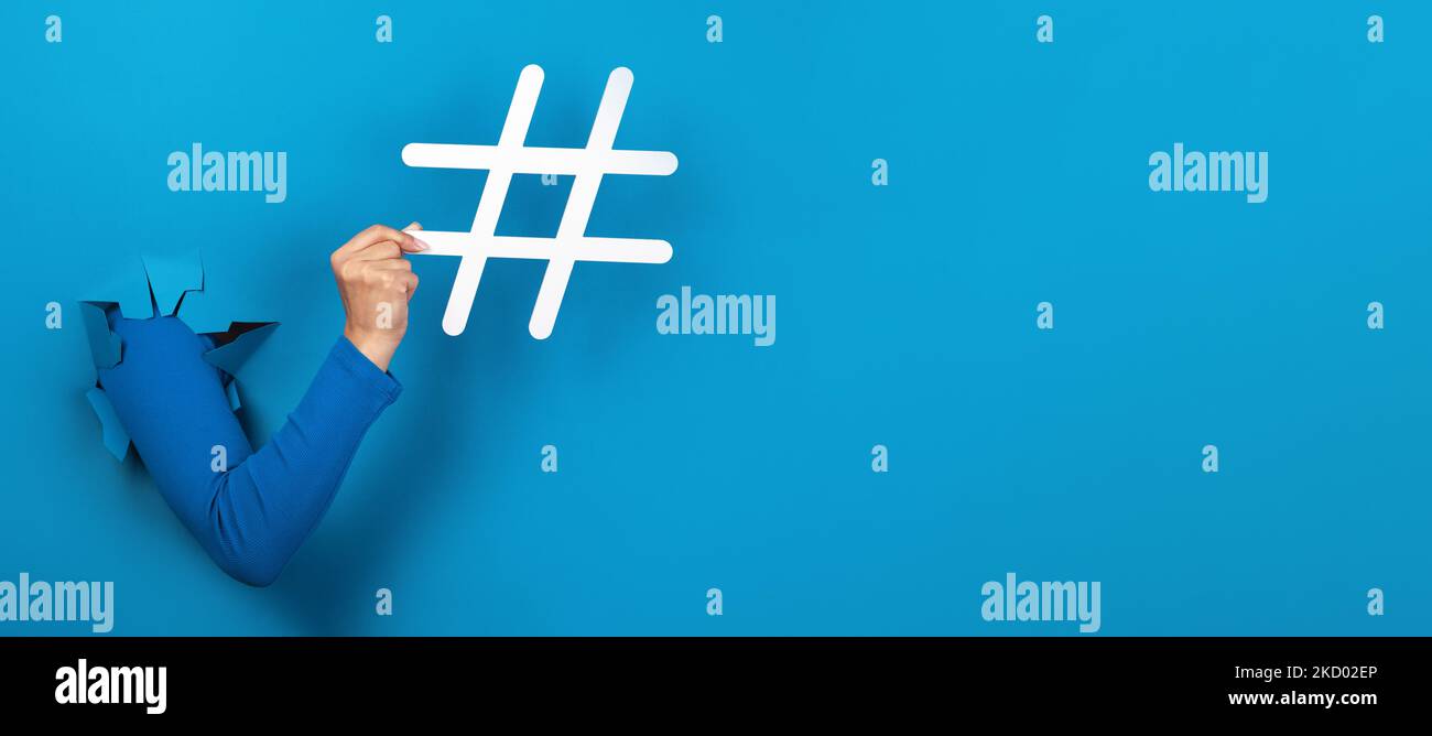 hand holding hashtag sign over blue background, social media concept ...