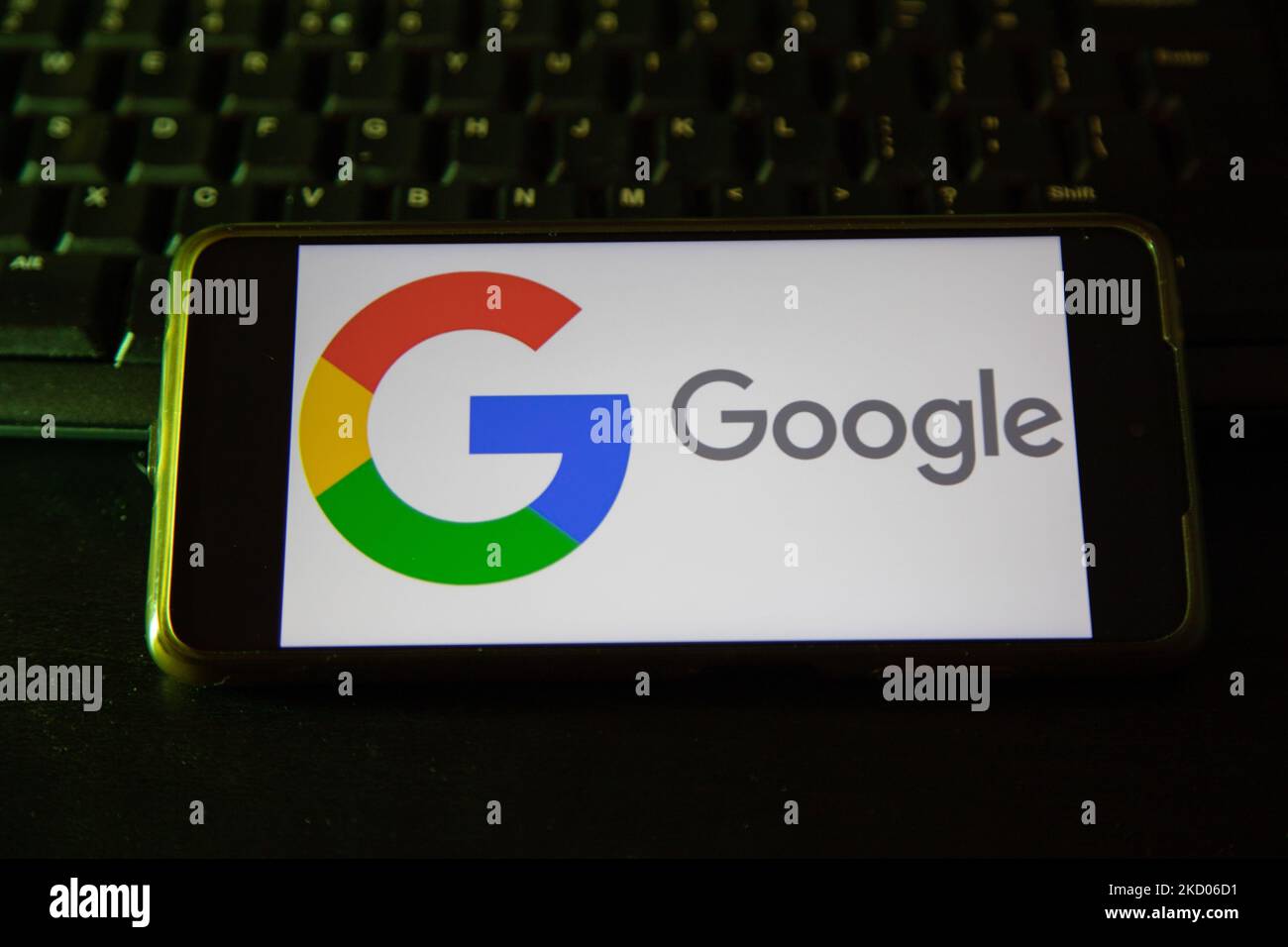 Google logo on smartphone display and a keyboard in the background ...