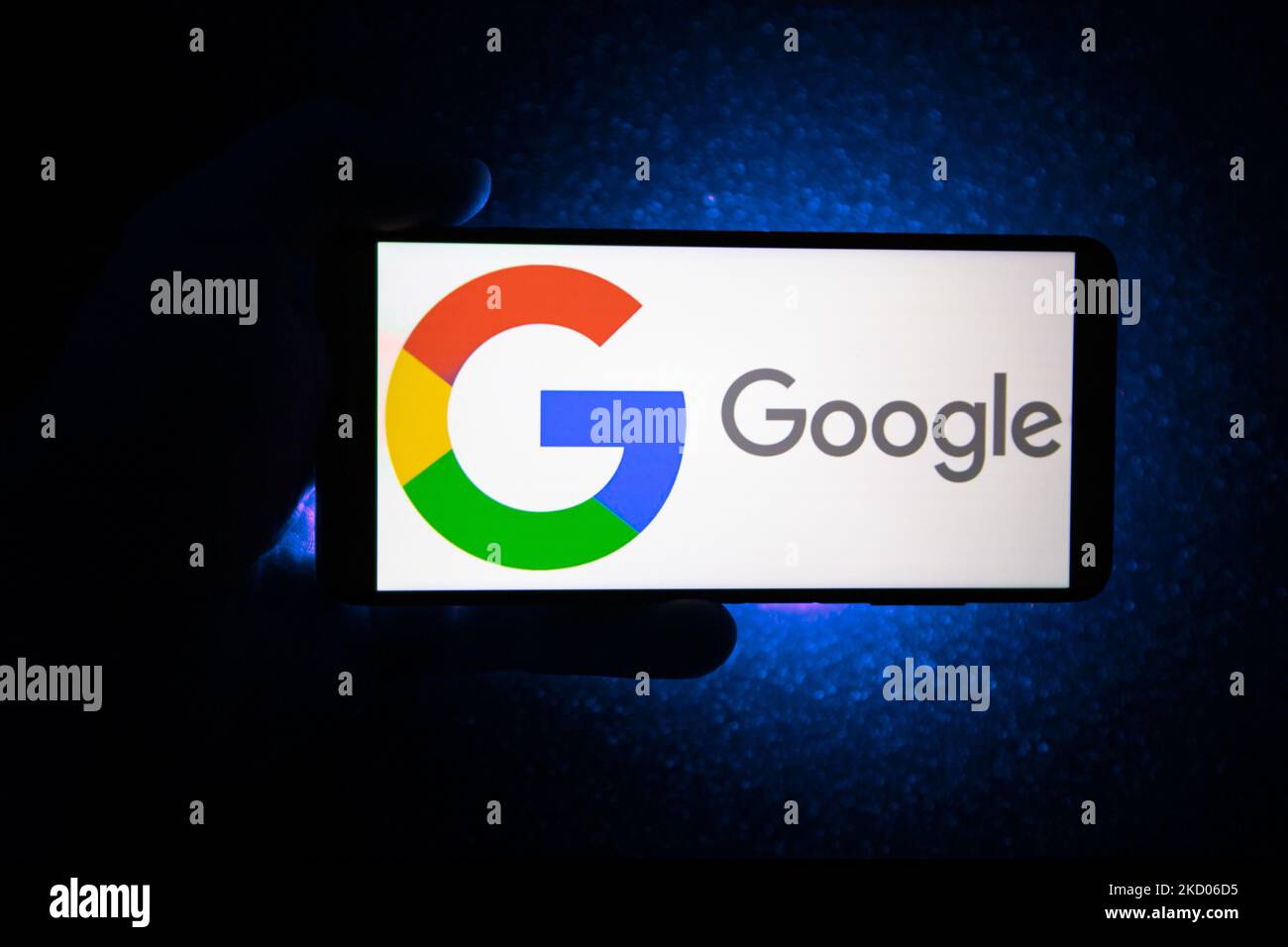Hand is holding a smartphone with the Google logo displayed and dark ...
