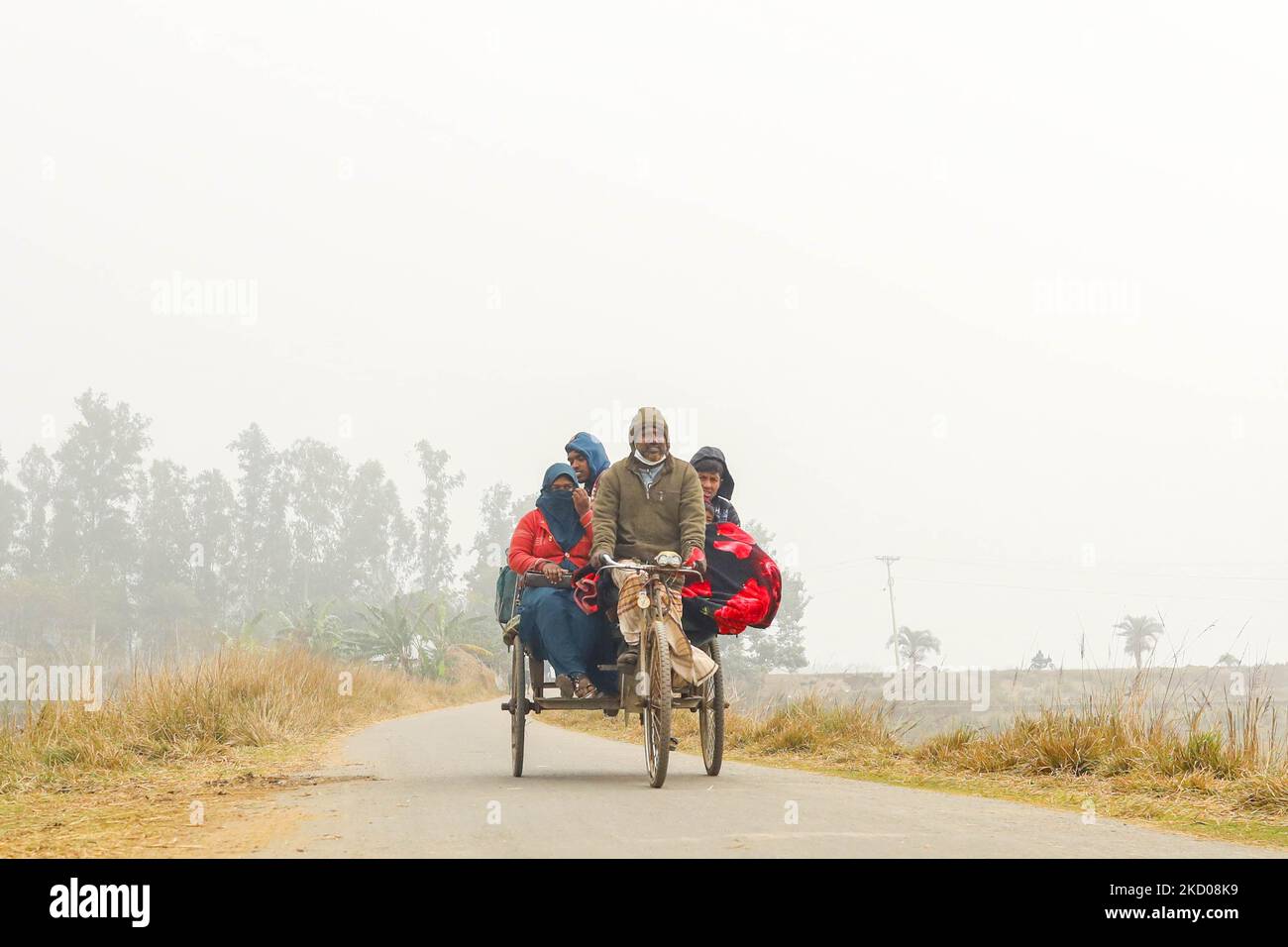 A rickshaw van driver takes passengers to their destination on a foggy ...