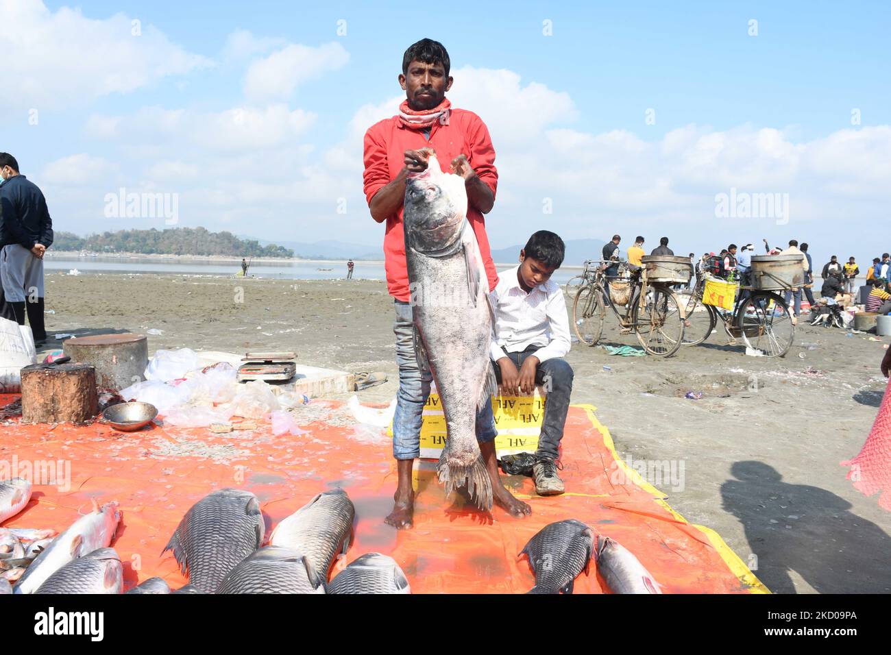 A vendor carries a fish to attract customers to his stall at a market ...