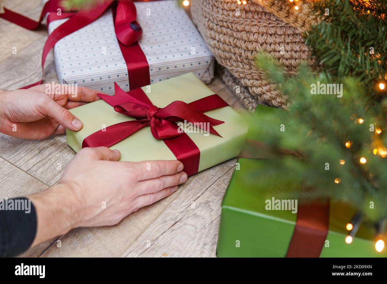 Man putting Christmas gift box under Christmas tree in living room ...