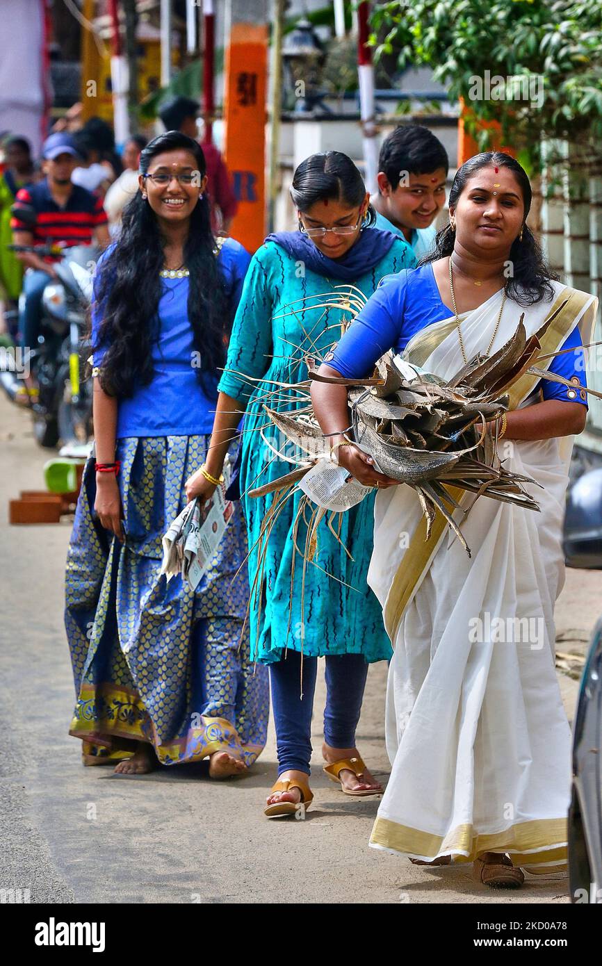 Hindu woman carries a bundle of dried coconut flower sheaths (kothumbu ...
