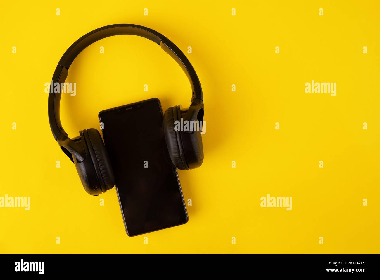 black headphones around a blank screen smartphone over yellow ...