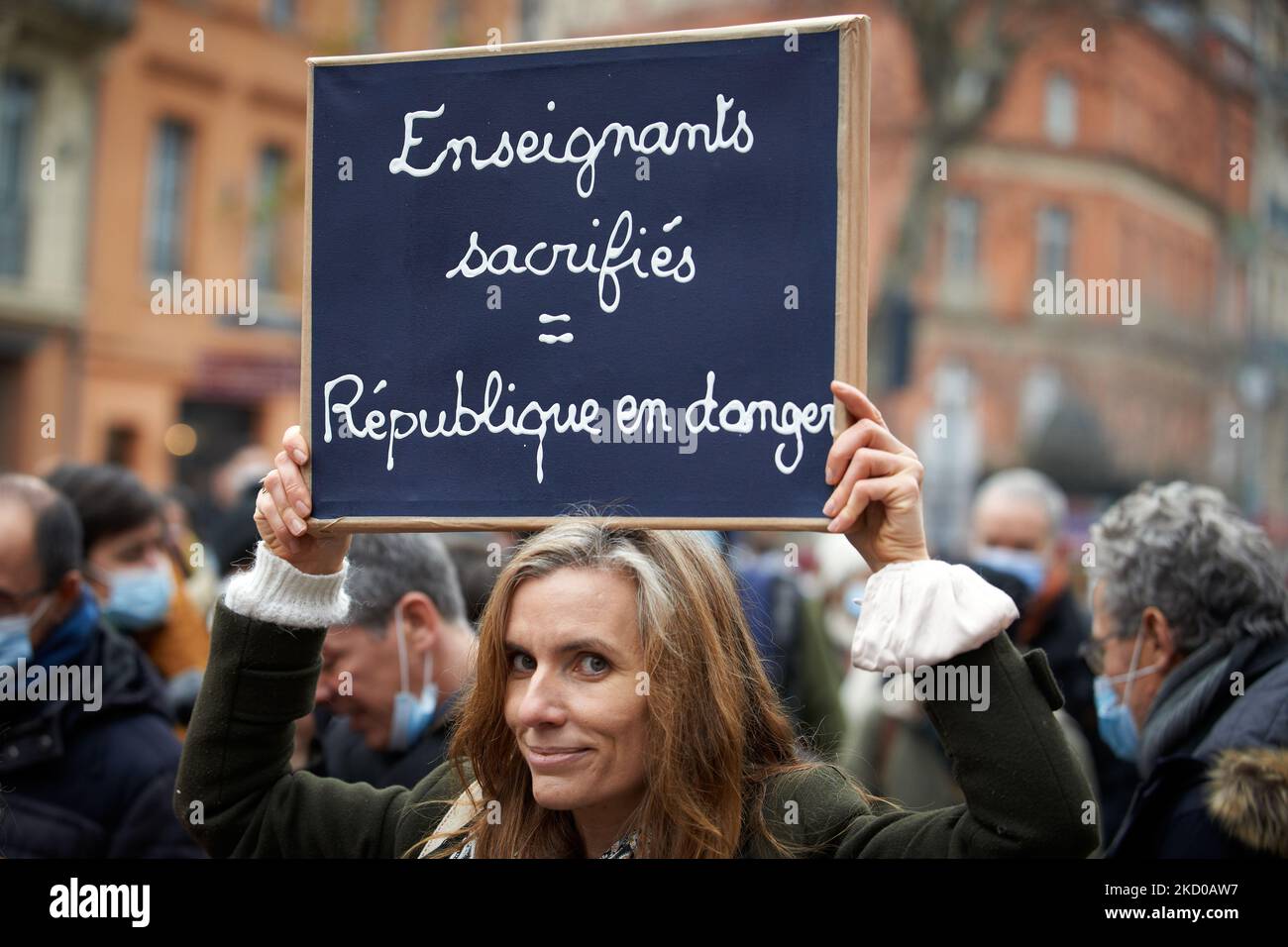 A teacher holds a cardboard reading 'Sacrified teachers : Republic in ...