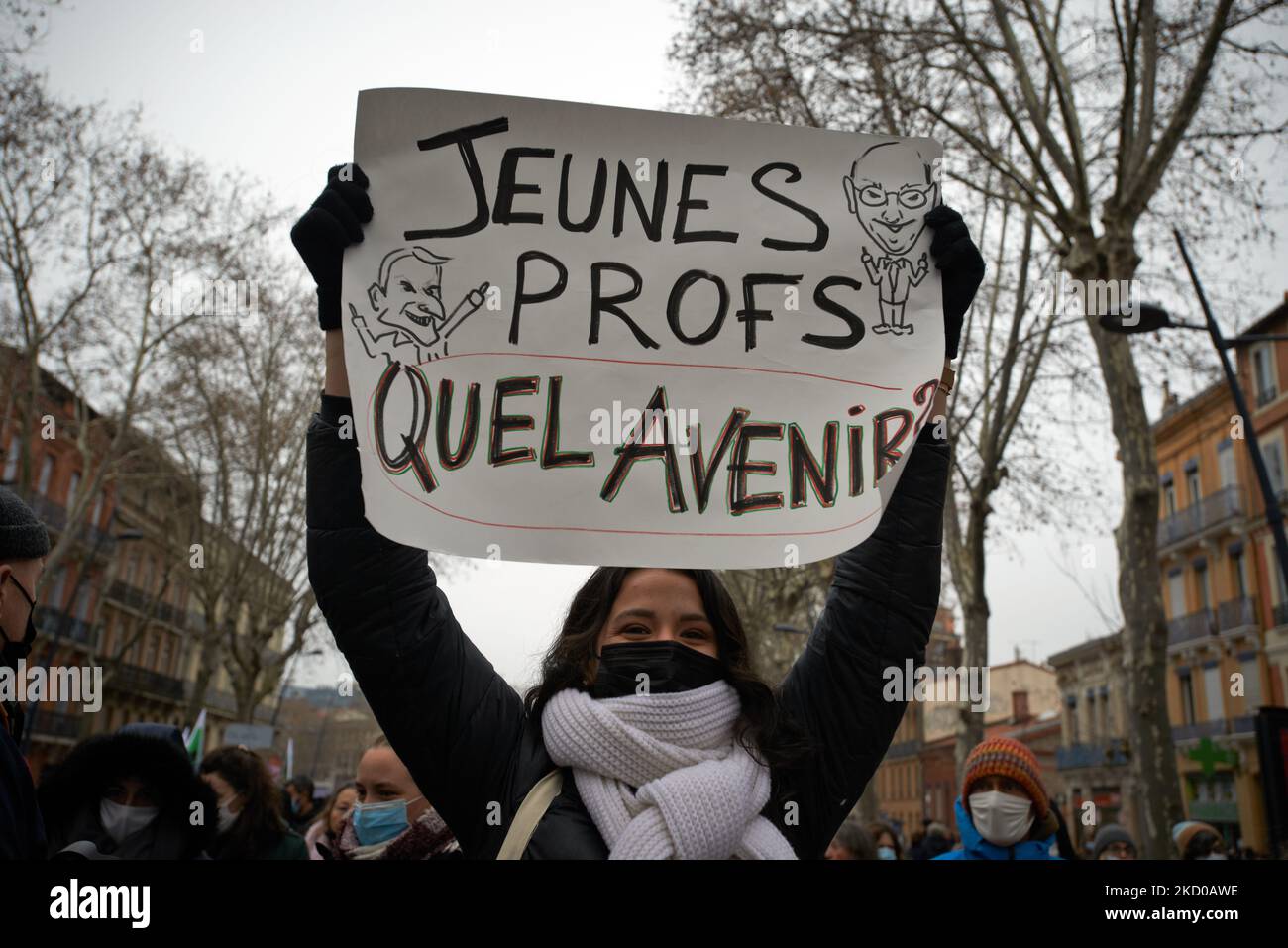 A young teacher shows a placard depicting Macron and Blanquer and ...