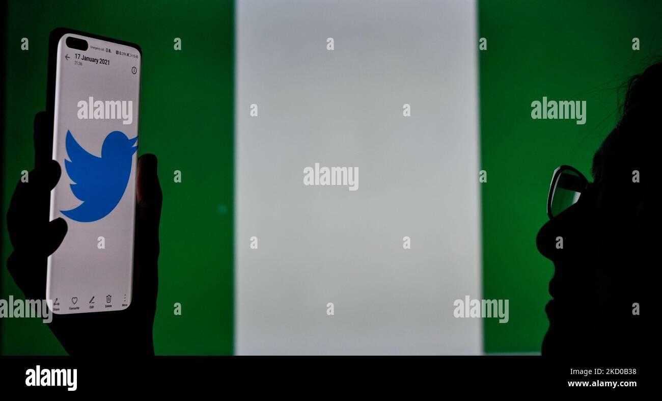 An image of a woman holding a mobile phone with the Twitter logo in ...