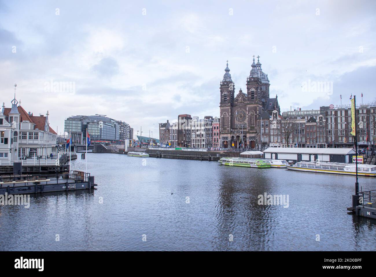 The canals and parked boats in Amstedam with the Basilica of Saint ...