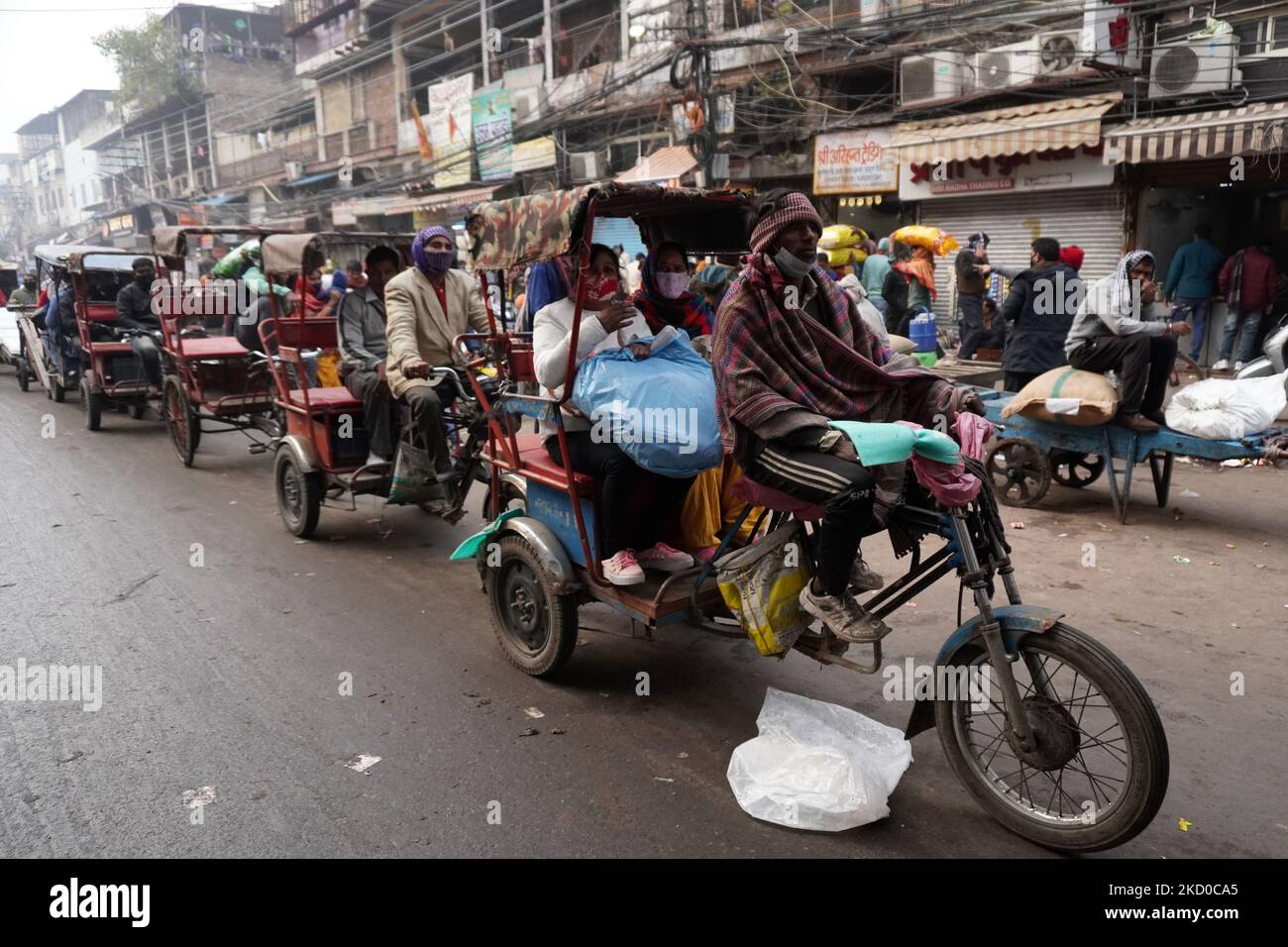 Electric rickshaws ply through a busy wholesale market, amidst the ...