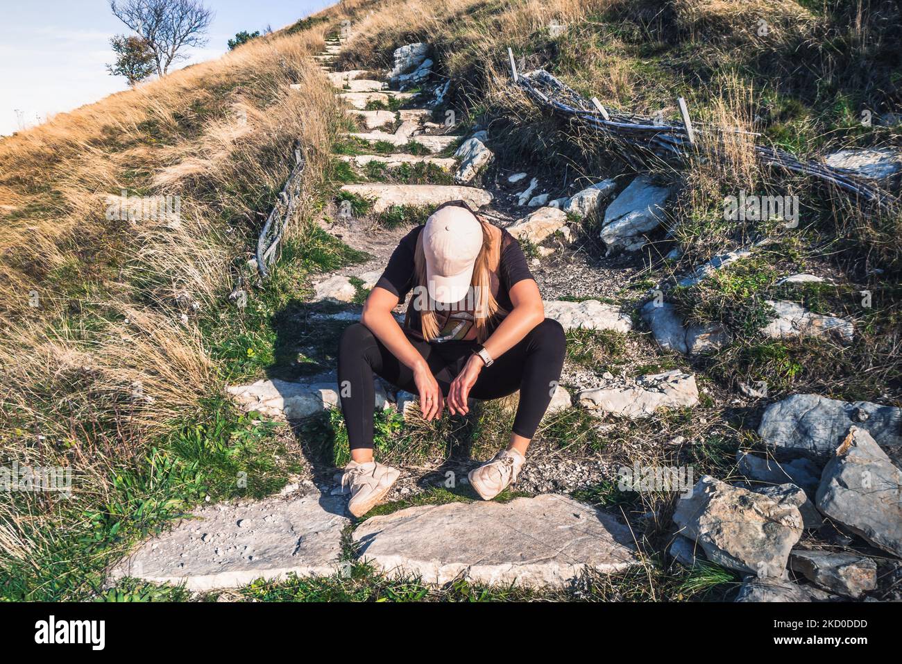 Tired woman sitting on stone steps while climbing to the top of the ...