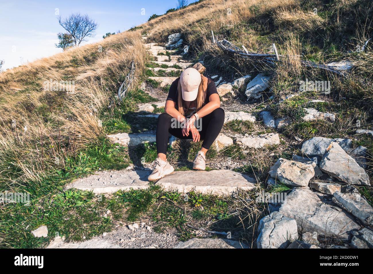 Tired woman sitting on stone steps while climbing to the top of the ...