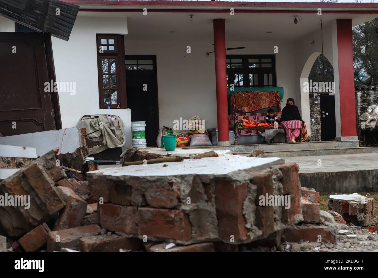 A woman with her kid sit outside their home in Roop Nagar Jammu, Jammu ...