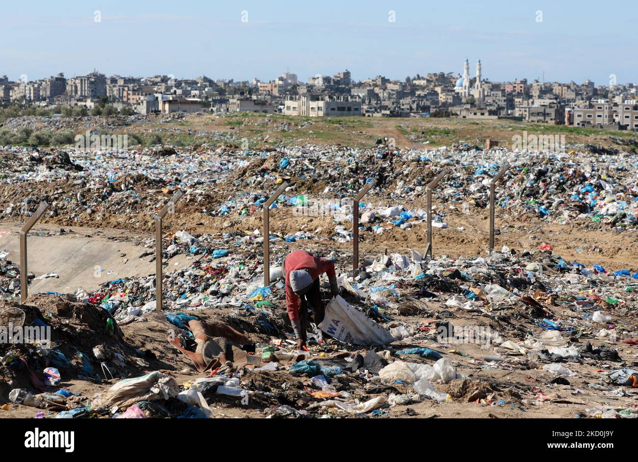 A Palestinian youth collects plastic and metal from waste piles ...