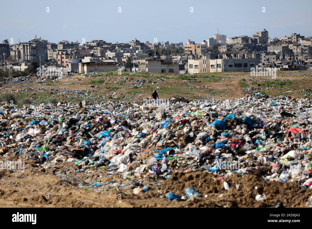 A Palestinian youth collects plastic and metal from waste piles ...