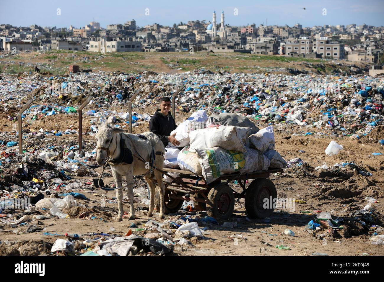 A Palestinian youth collects plastic and metal from waste piles ...