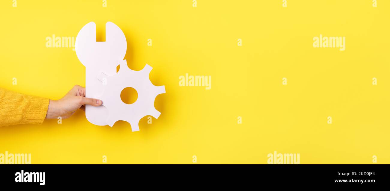 Service tools symbol in hand over yellow background, concept of repair ...